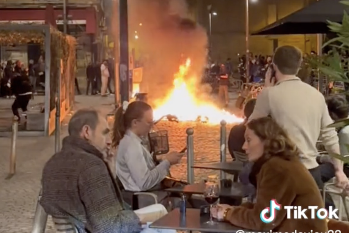 French diners enjoy glass of wine as city burns in background during ...