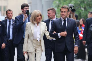Macron and wife Brigitte smile and hold hands as they board plane after ...